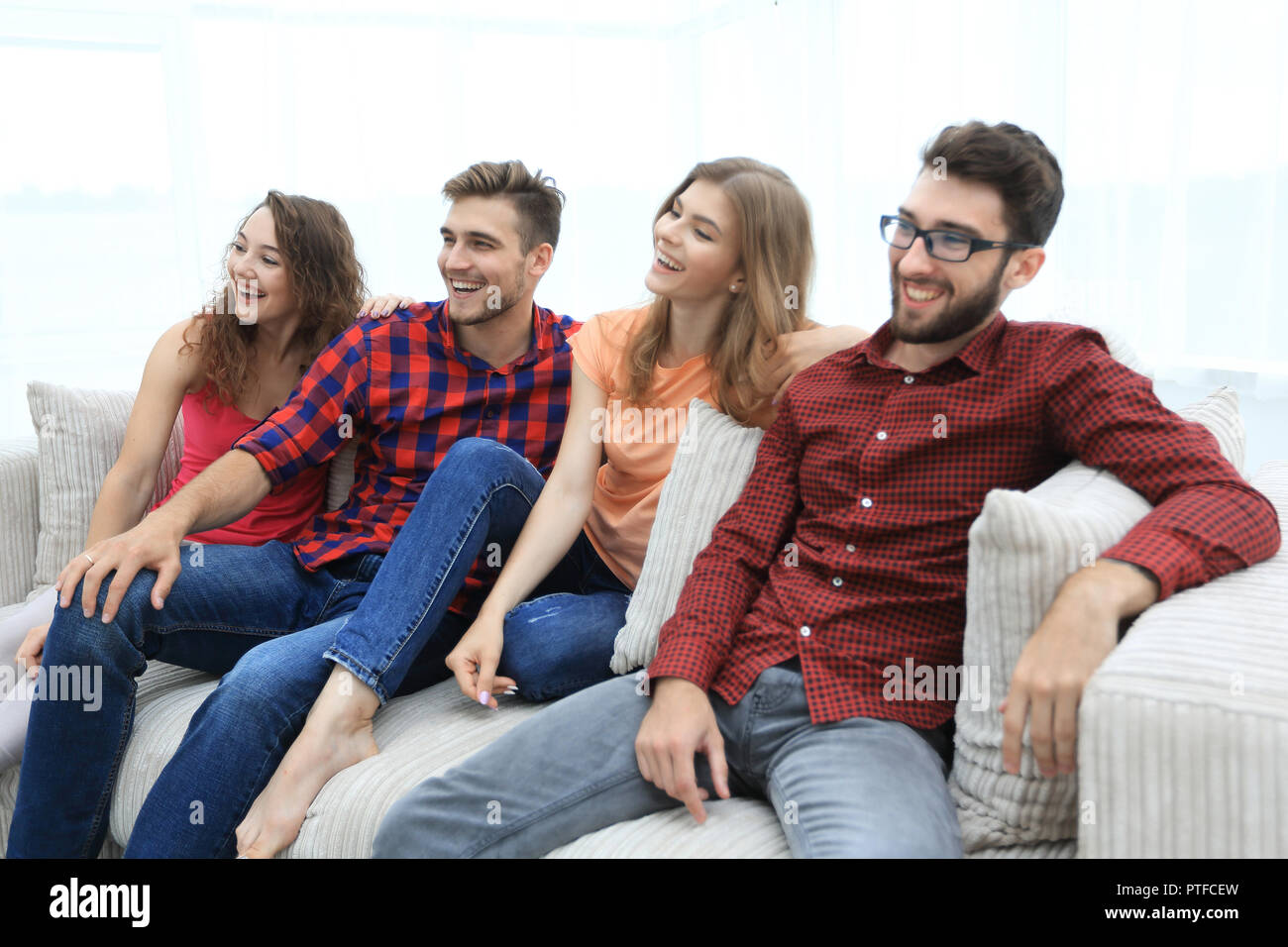 group of smiling young people sitting on the couch Stock Photo - Alamy