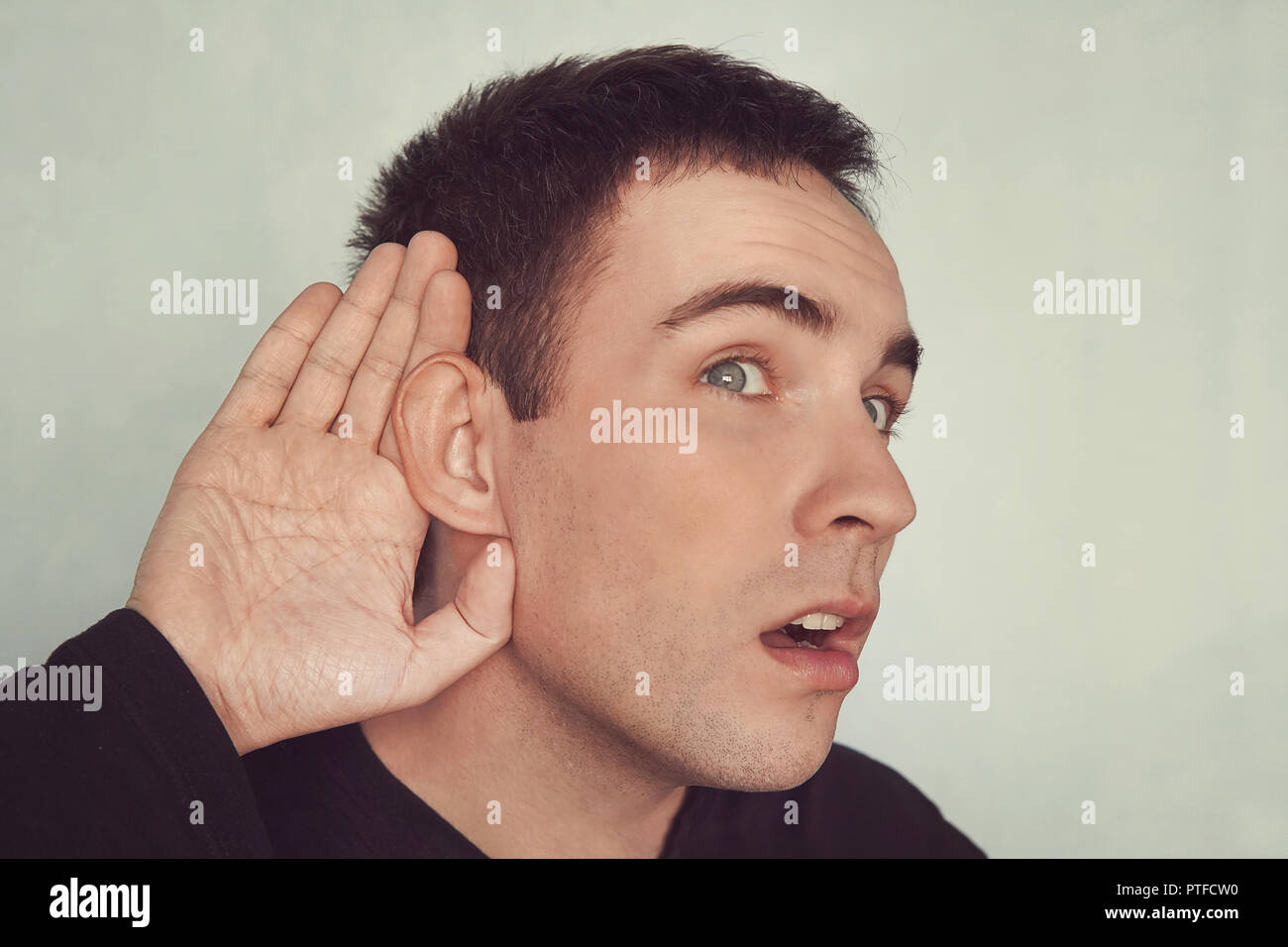 Portrait of young casual man which overhears conversation over blue ...