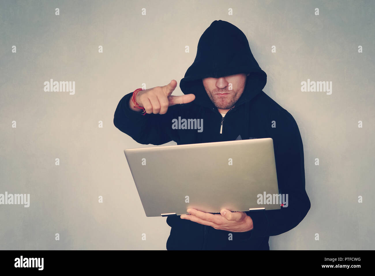 Hacker holding gun working on his computer terrorist and bandit concept ...