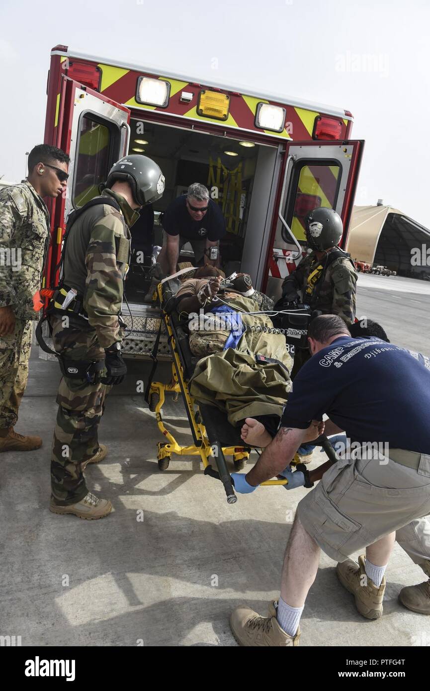 Emergency medical services personnel lift a patient on to an ambulance ...