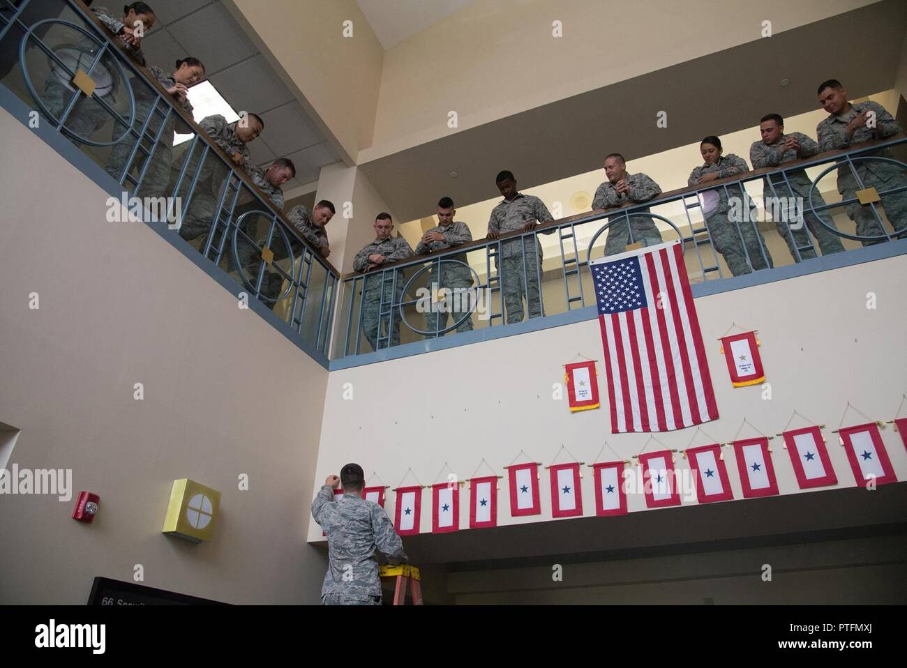 A member of the 66th Security Forces Squadron hangs a service banner ...