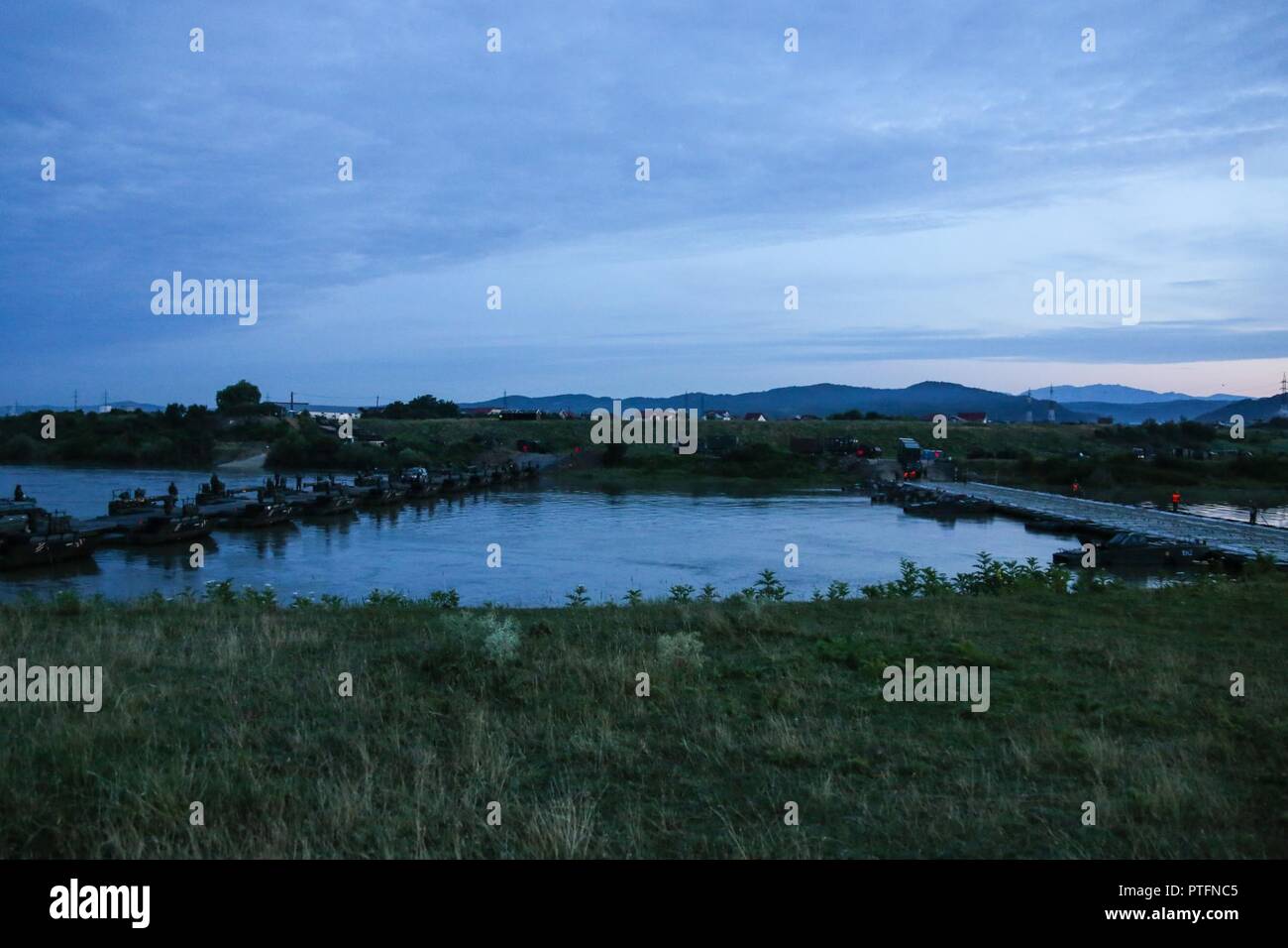 NATO soldiers move their vehicles across constructed bridges while ...