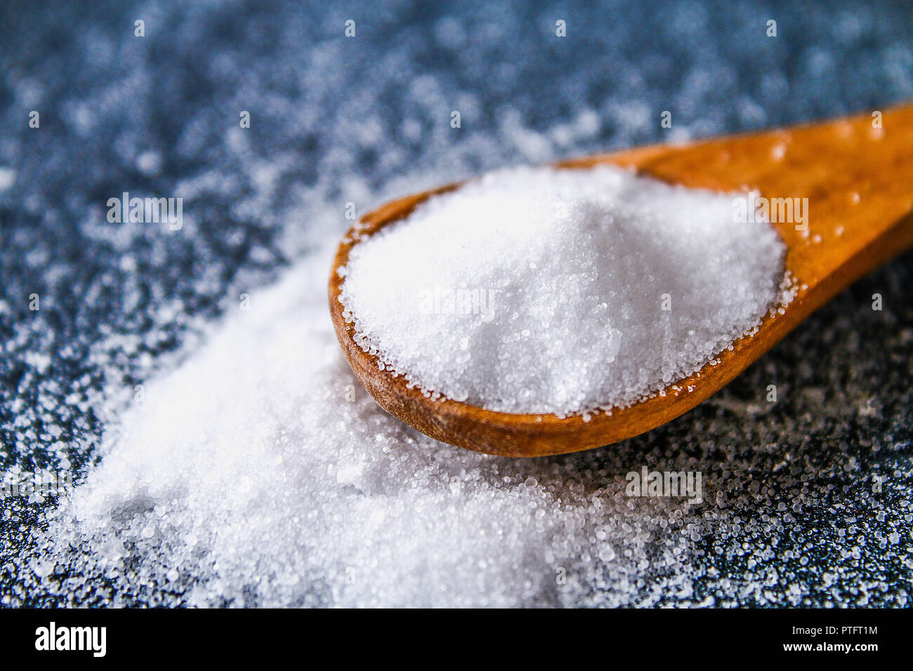 Crystals of shallow salt in a scoop, spoon on a dark gray table ...