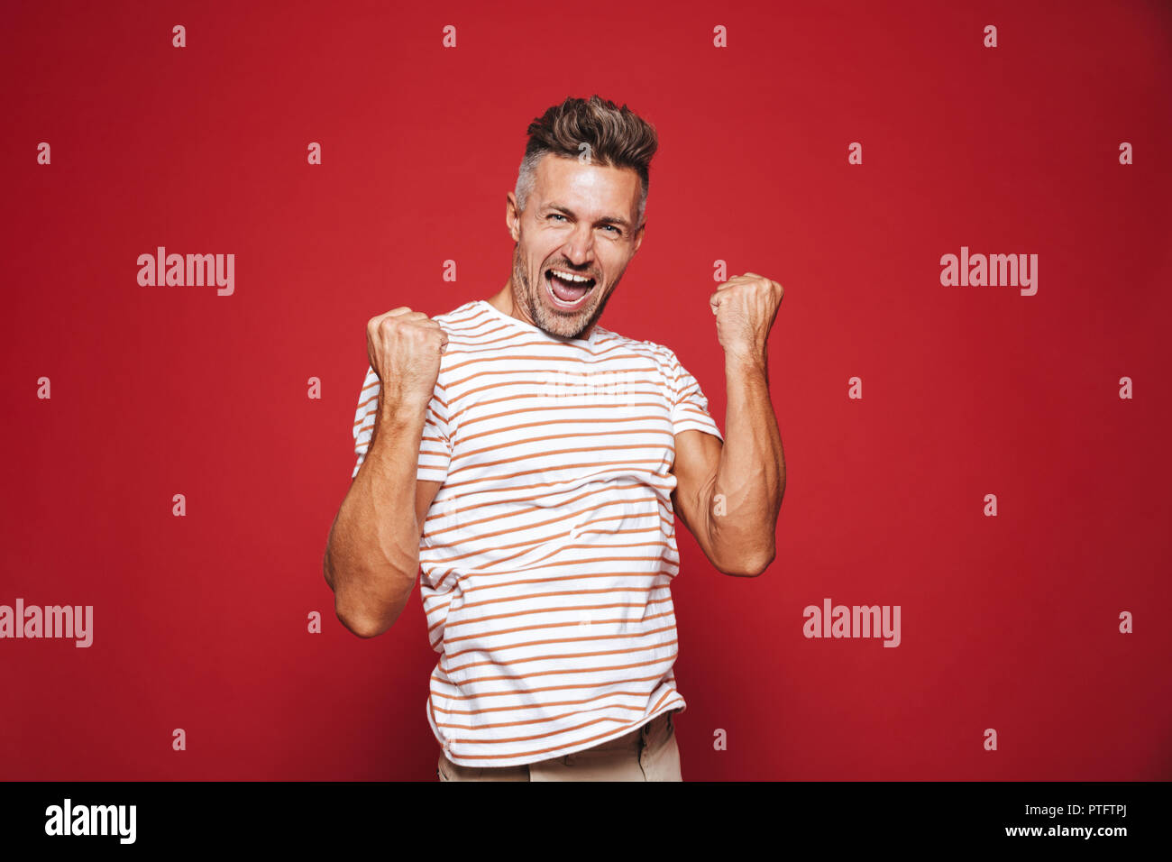European man in striped t-shirt screaming and clenching fists isolated ...
