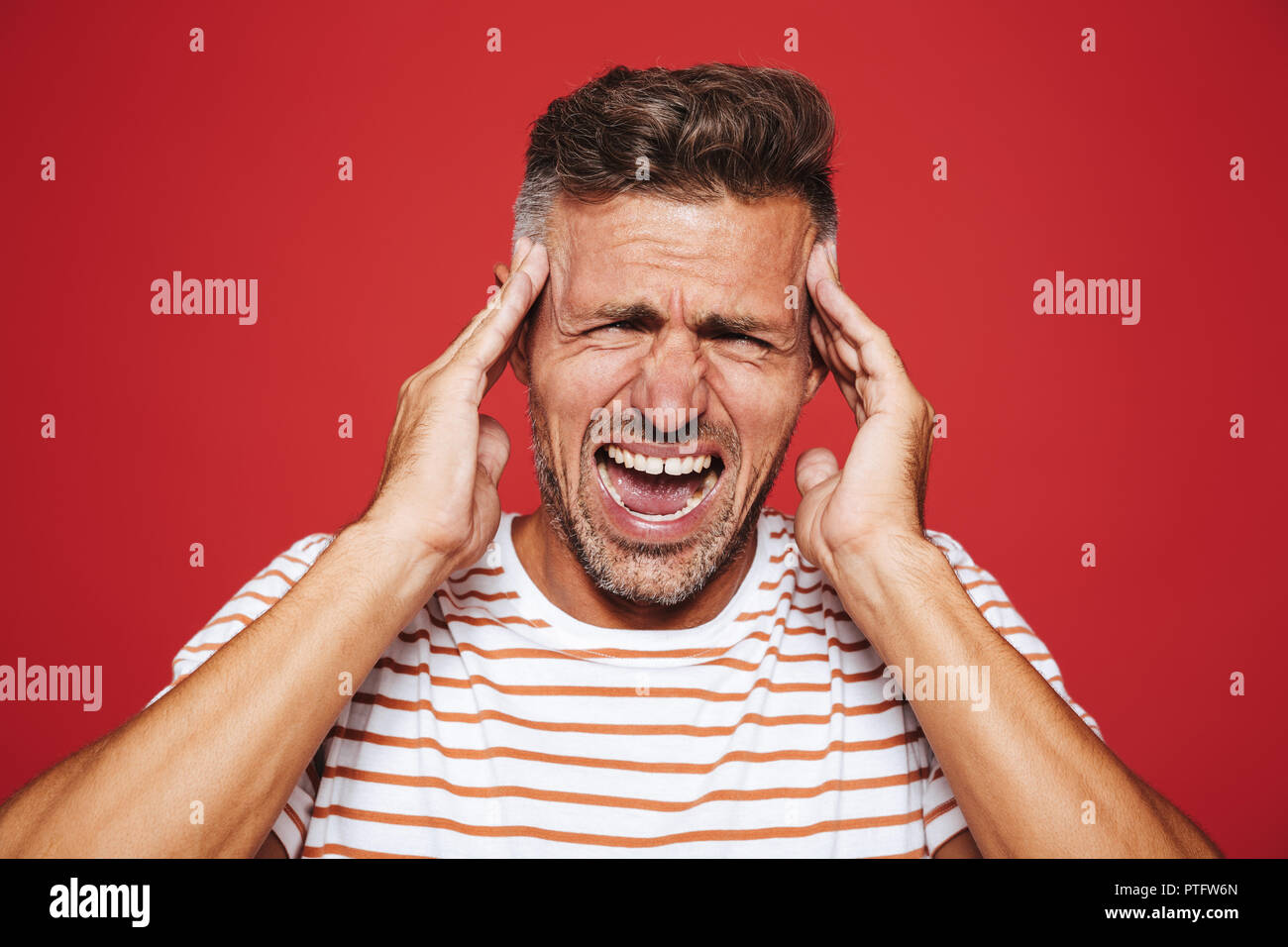 Adult man in striped t-shirt screaming and rubbing temples because of ...