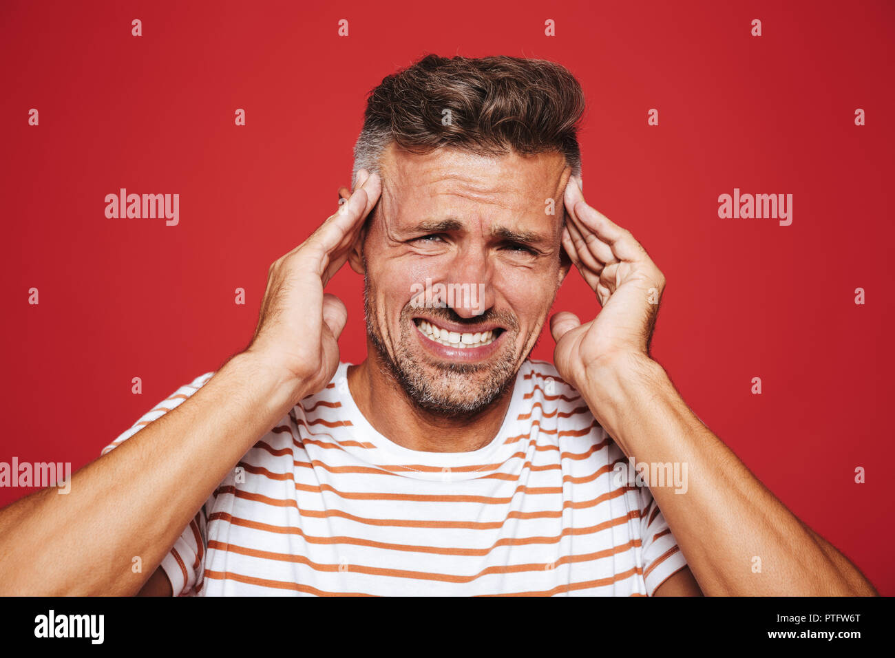 Unhappy man in striped t-shirt screaming and rubbing temples because of ...