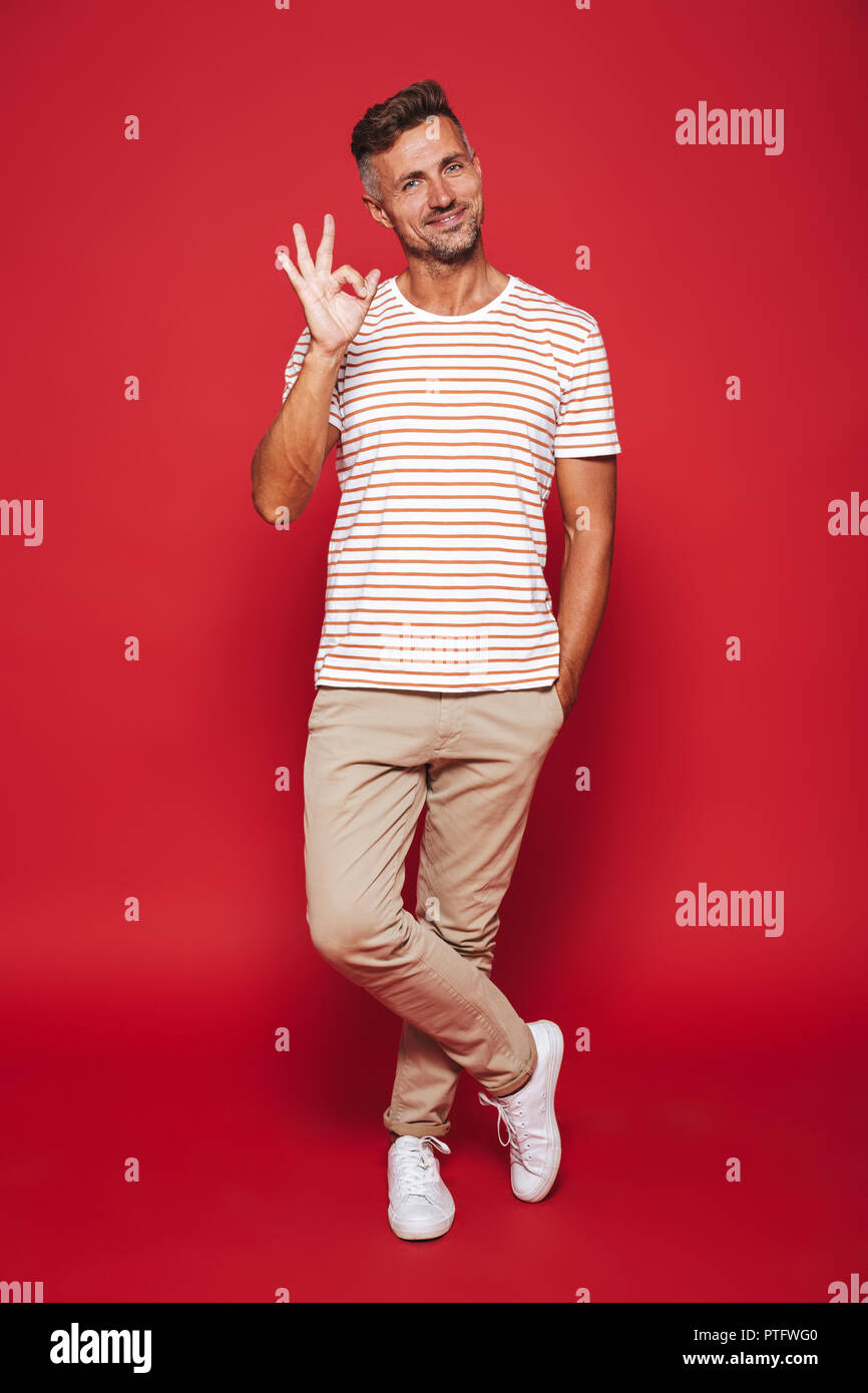 Full length photo of brunette man in striped t-shirt smiling and ...