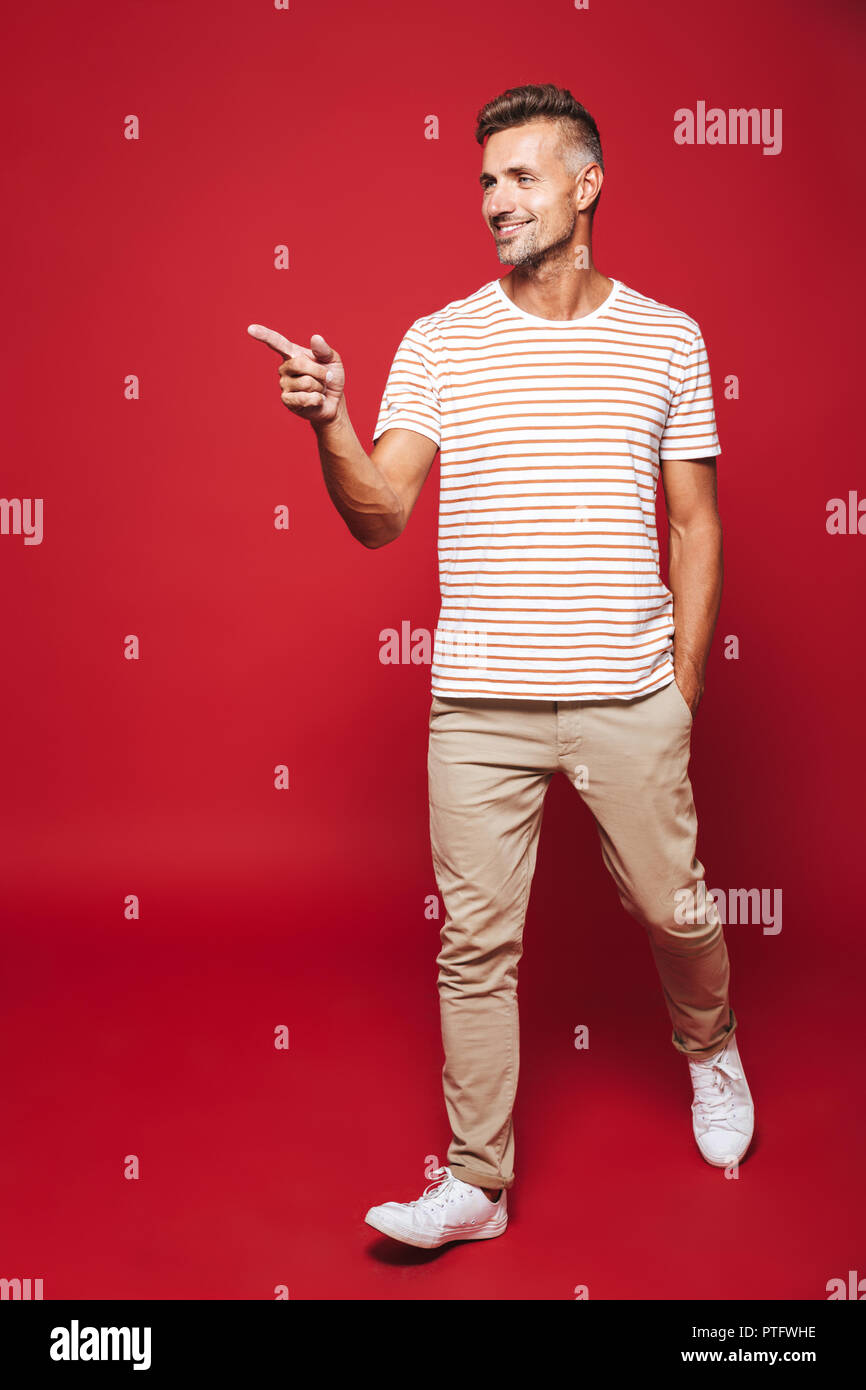 Full length photo of young man in striped t-shirt gesturing index ...