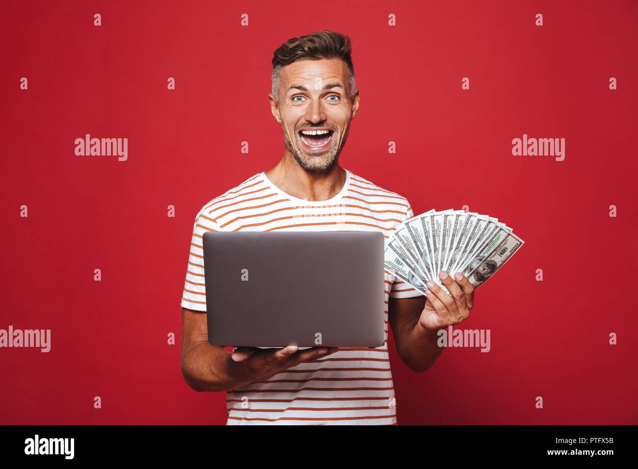 Image of excited man in striped t-shirt smiling while holding fan of ...