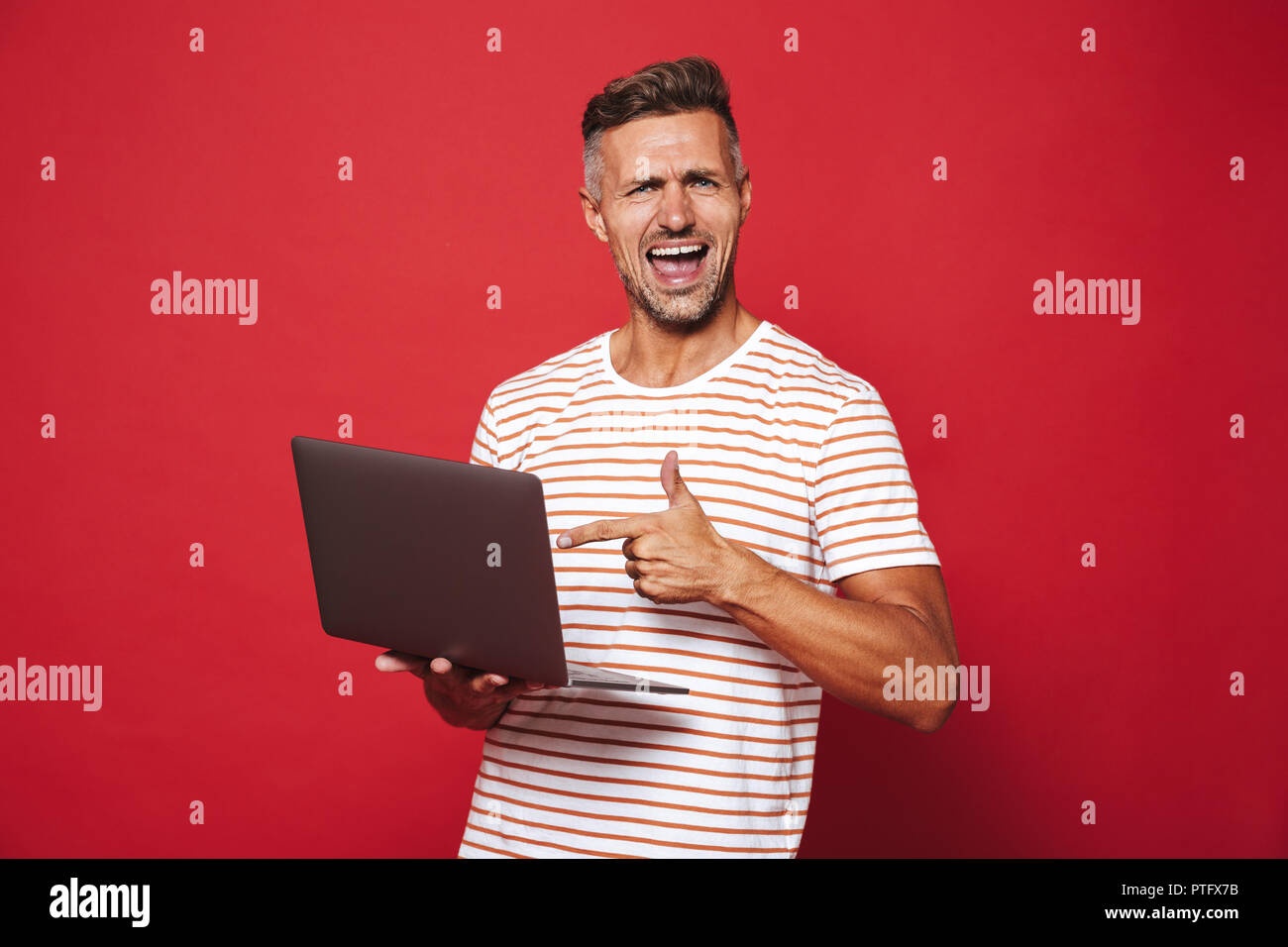 Image of attractive man in striped t-shirt smiling and holding gray ...