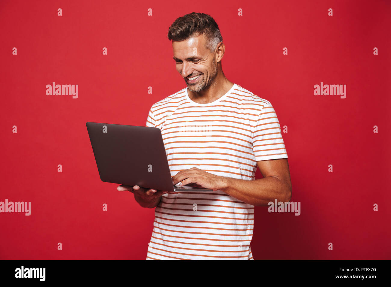 Image of brunette man in striped t-shirt smiling and holding gray ...