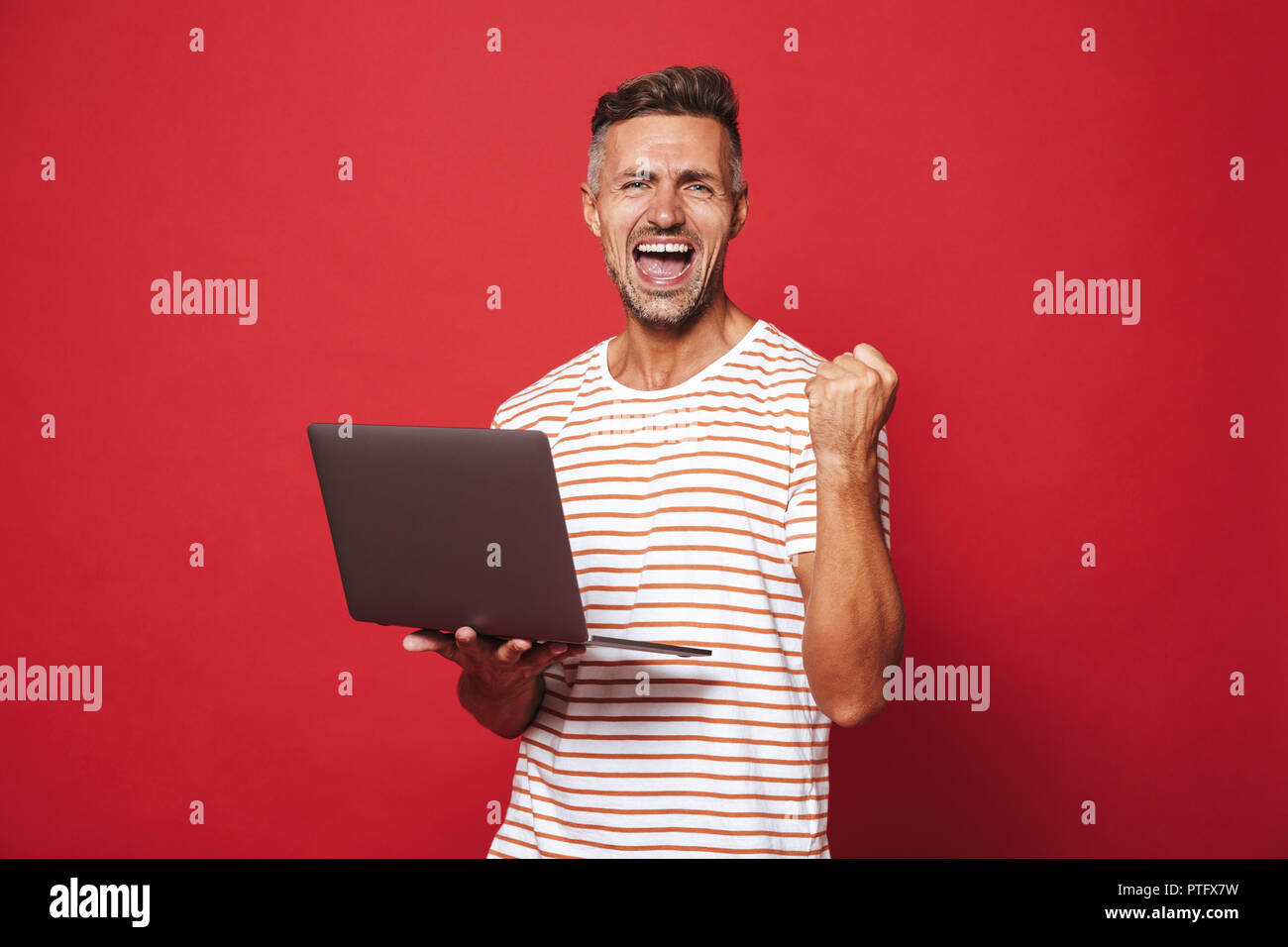 Image of successful guy in striped t-shirt smiling and holding gray ...