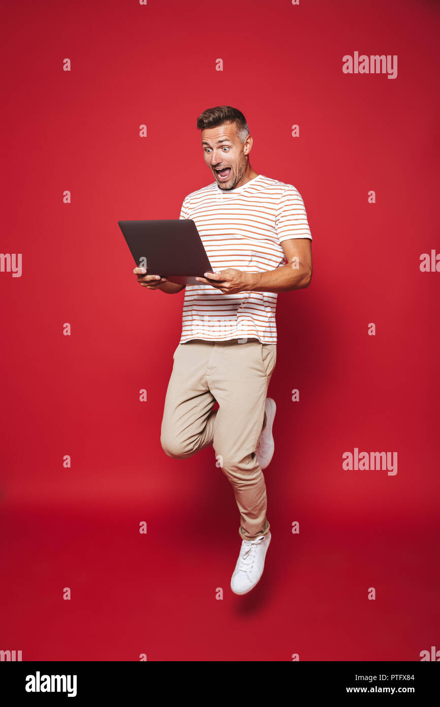 Full length photo of joyful man in striped t-shirt smiling and holding ...
