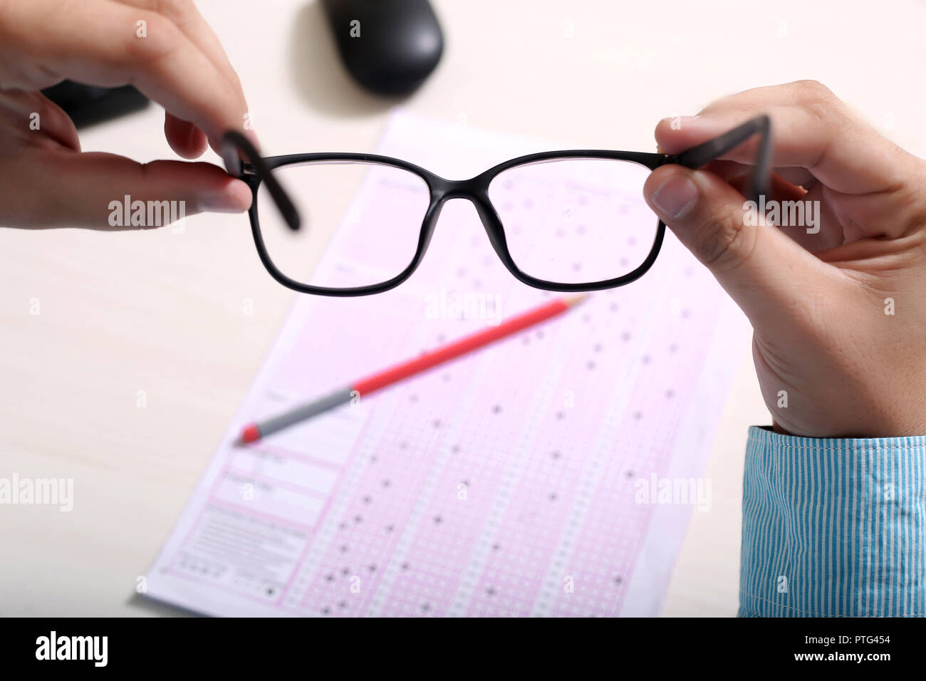 Man is holding glasses in hand. Picture of mouse, pencil and OMR sheet ...