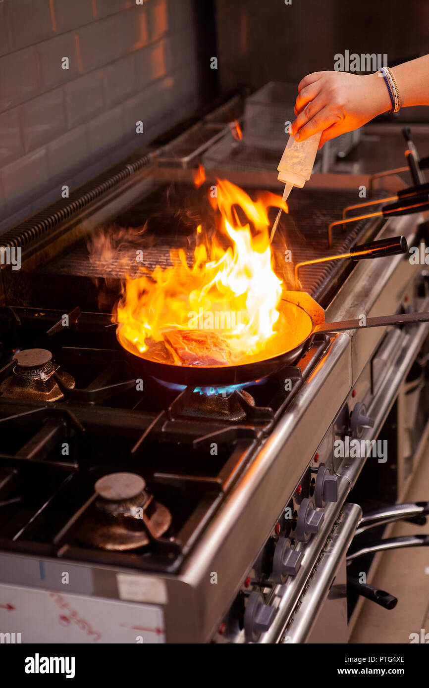 Chef cooking with high fire in kitchen restaurant Stock Photo - Alamy