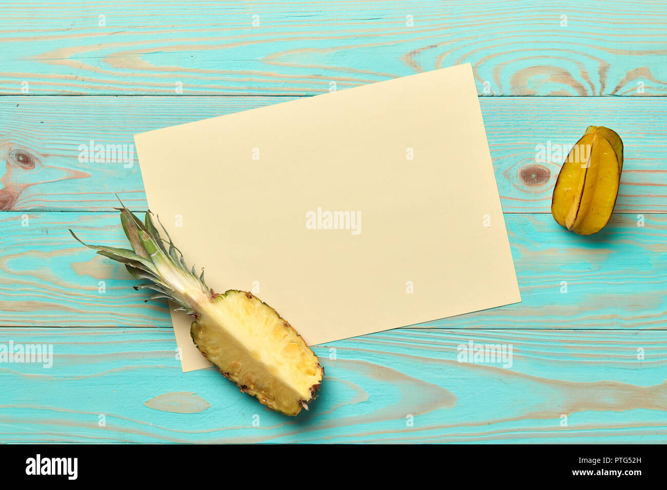 White cardboard with a slice of pineapple and a whole carambola on a ...