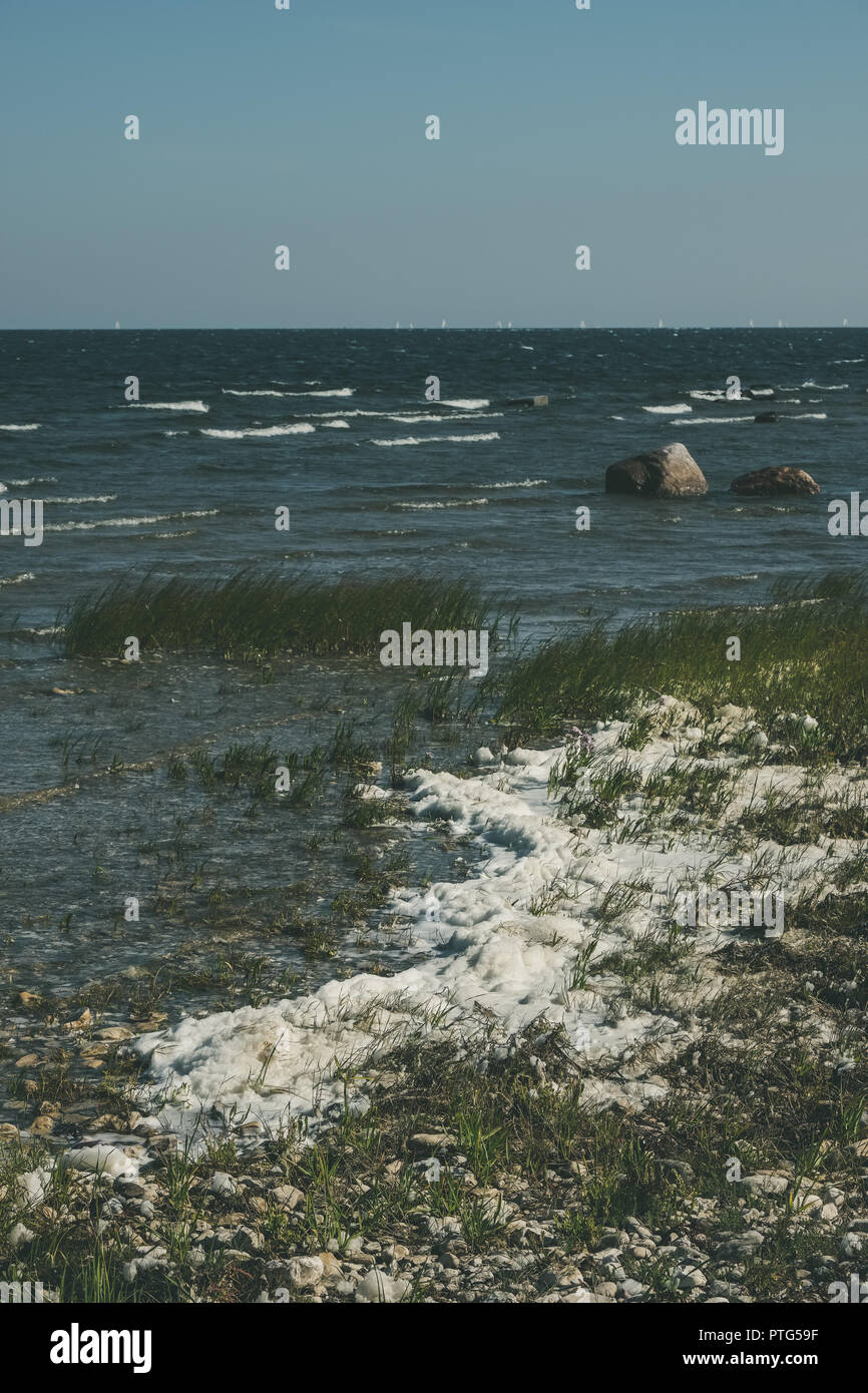 rocky sea beach with wide angle perspective over the sea with sunny sky ...