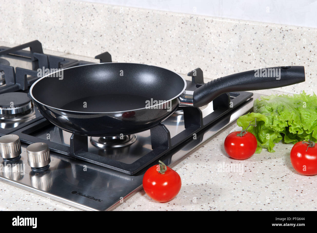 Black frying pan on a plate with tomatoes and lettuce leaves Stock ...