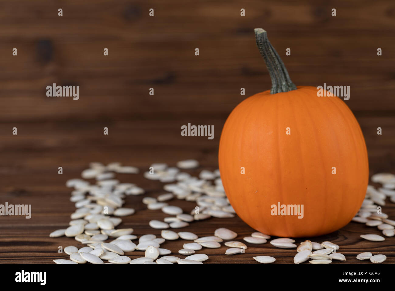 Fresh orange pumpkin and pimpkin seeds close-up on wooden background ...