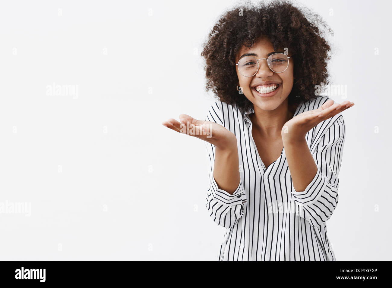 Studio shot of good-looking woman explaining something simple shrugging ...