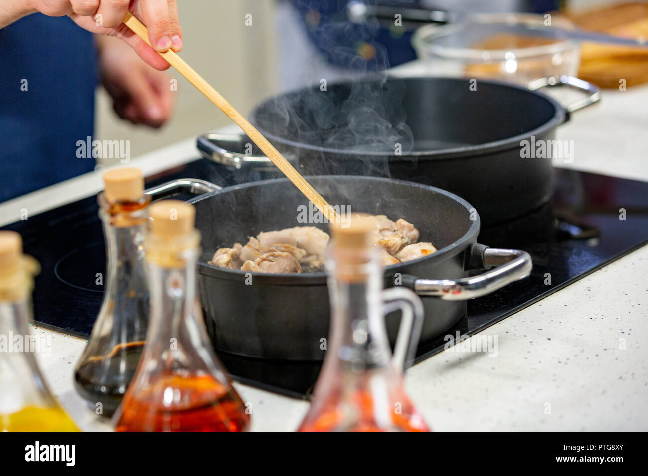 Man cooks meat in a frying pan. Hand using spatula to stir red and ...