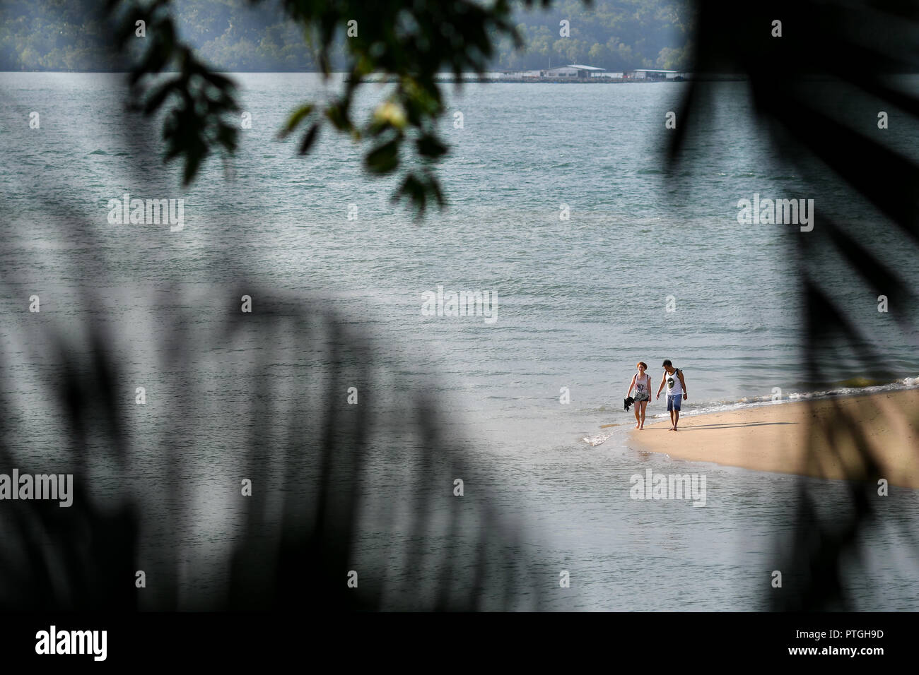 Couple walking along the sunny shoreline Stock Photo - Alamy