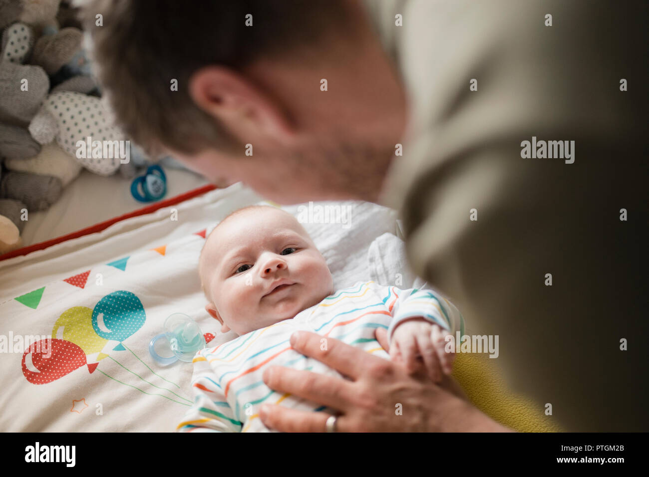 Mid-adult father checking up on his newborn baby boy while he is lying ...