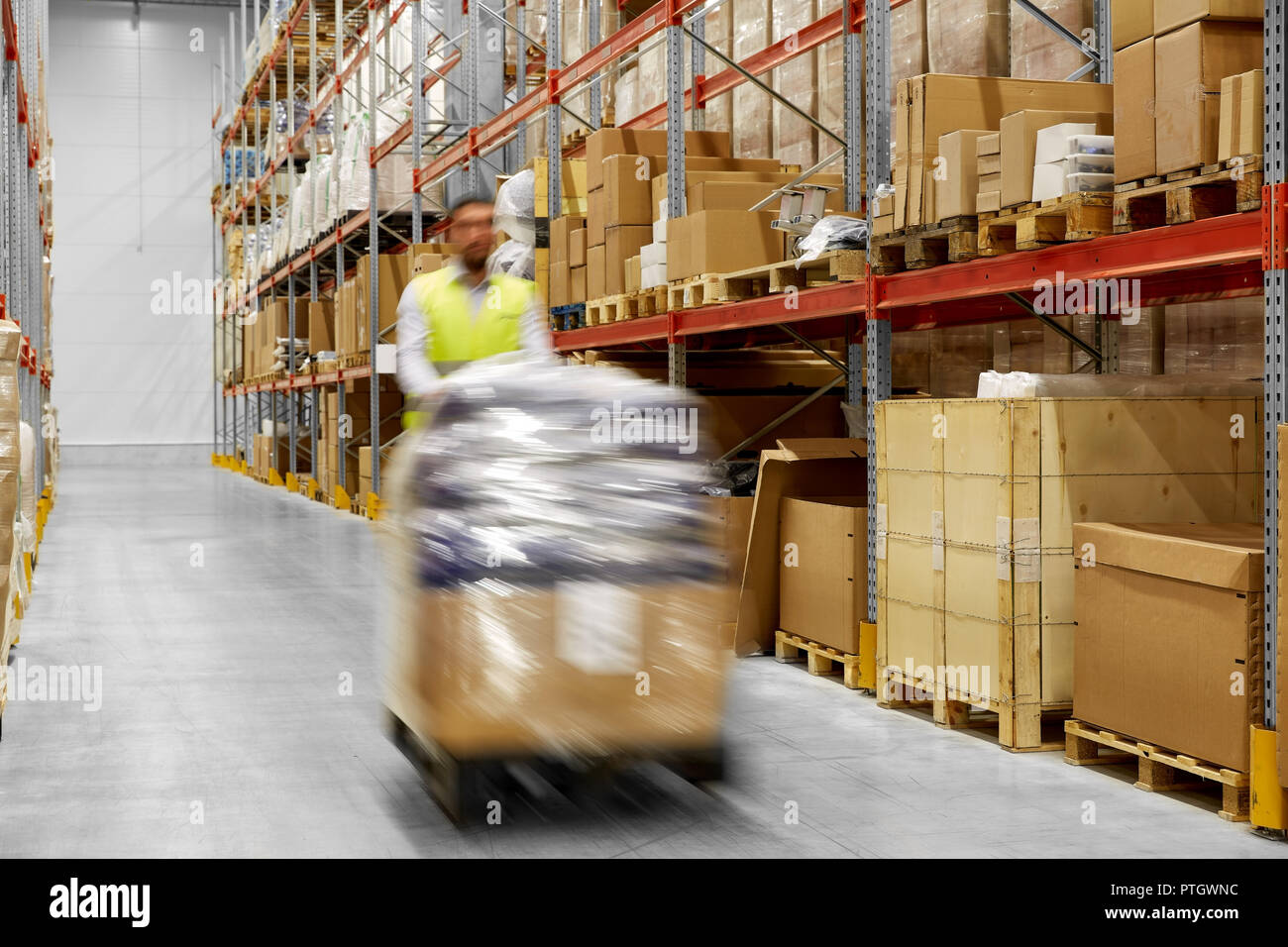 worker carrying loader with goods at warehouse Stock Photo - Alamy