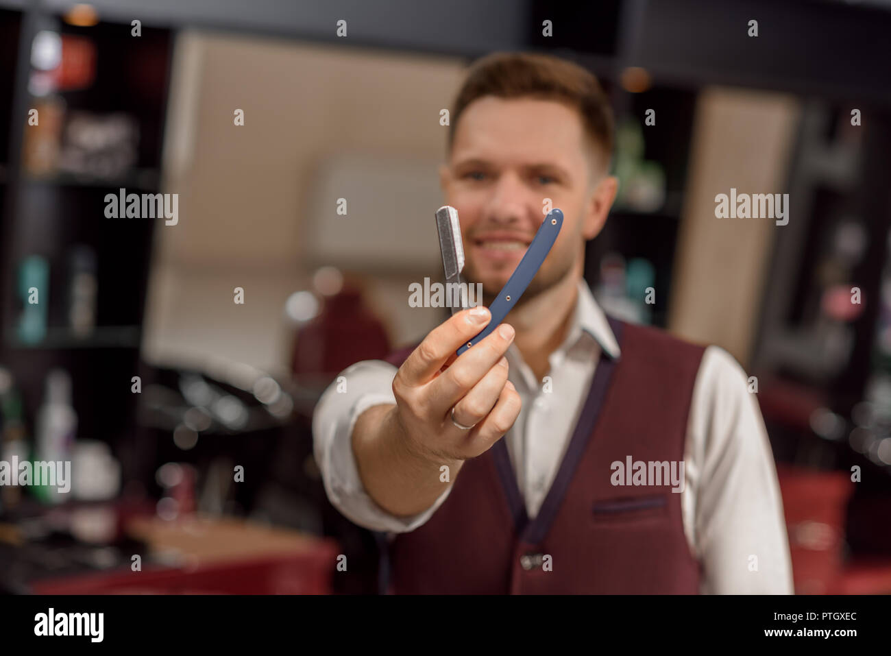 Male hairdresser looking at camera and holding instrument for shaving ...