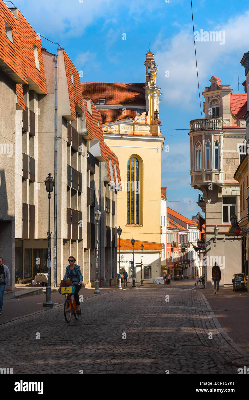 Vilnius old town, view on a summer morning of a young woman cycling ...