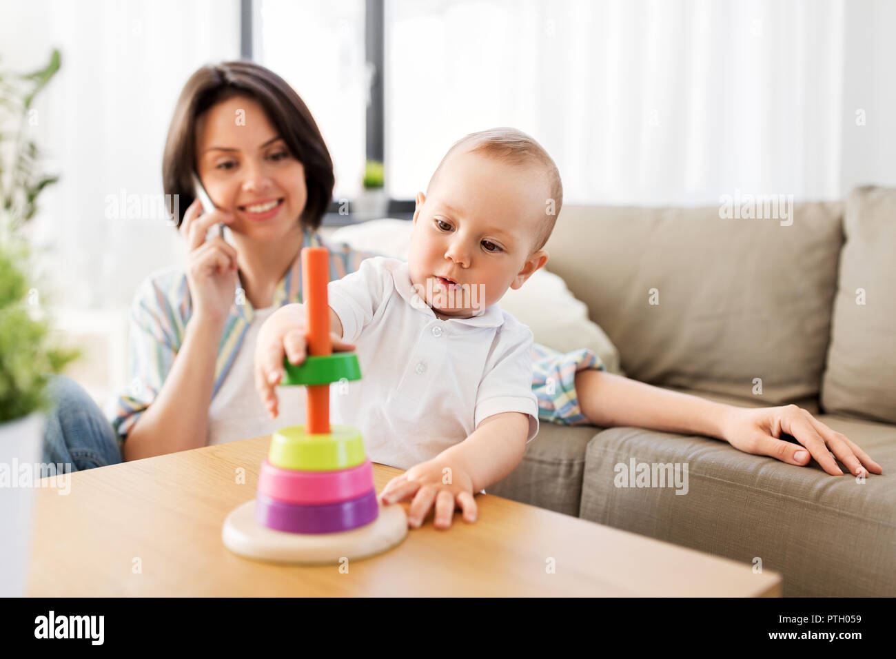 baby boy playing toy and mother calling on phone Stock Photo - Alamy