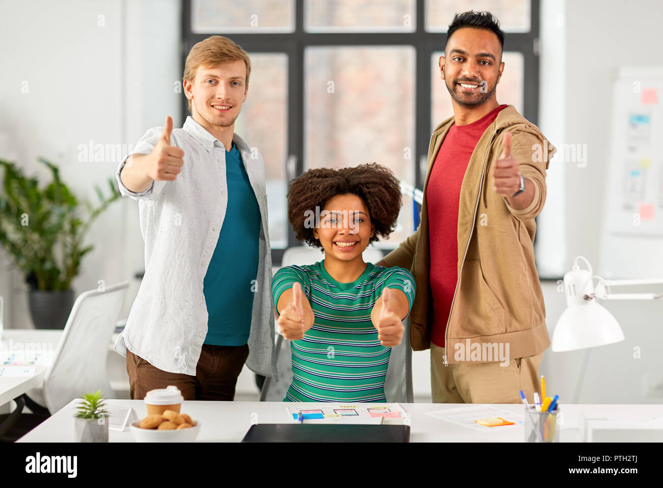 happy creative team showing thumbs up at office Stock Photo - Alamy