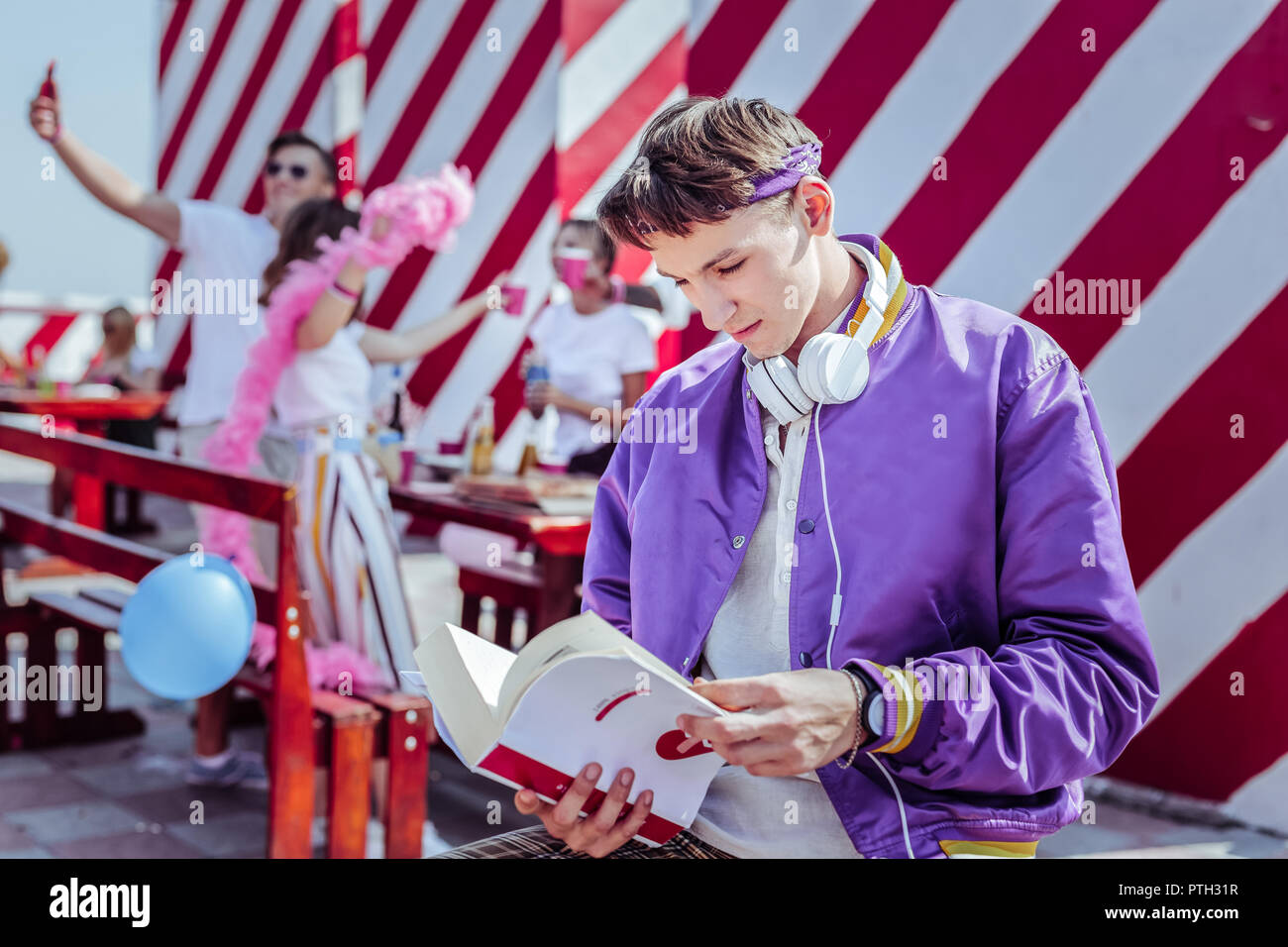 Pleased young man enjoying reading his book Stock Photo - Alamy