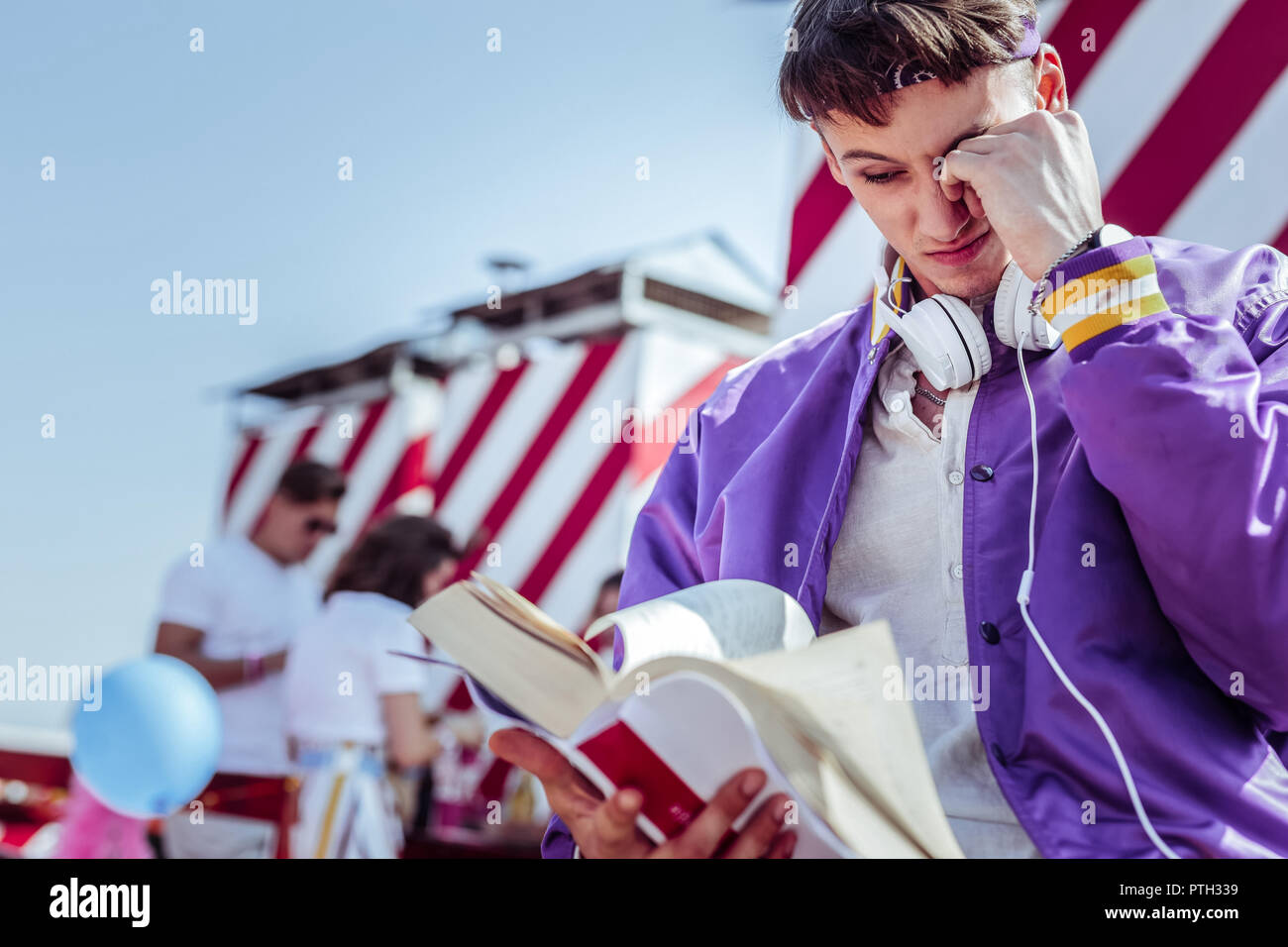 Tired hipster rubbing his eye while reading Stock Photo - Alamy