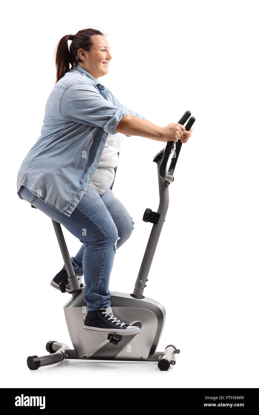 Overweight woman exercising on a stationary bicycle isolated on white ...