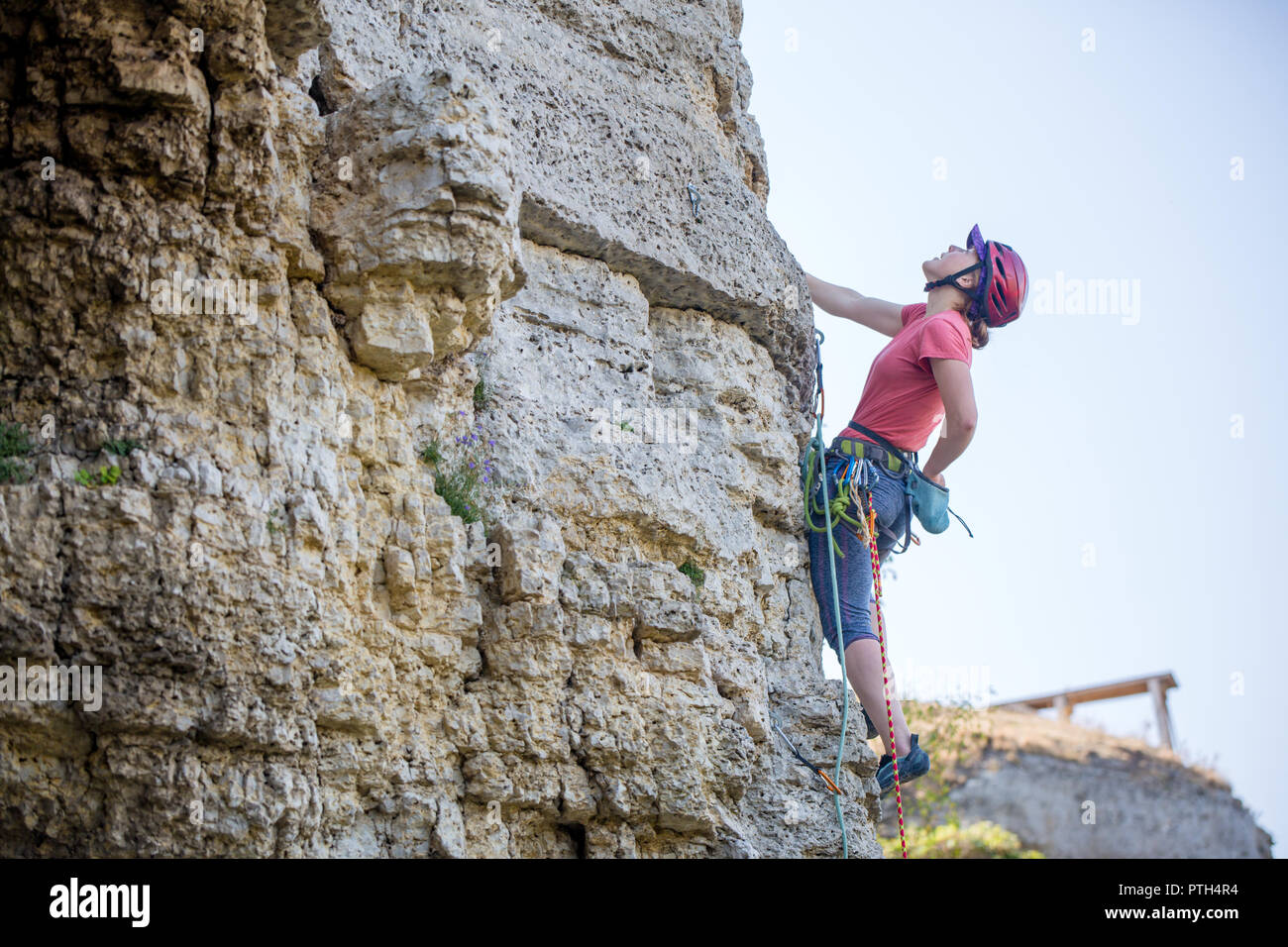 Photo of side view of young athlete woman in red helmet climbing up ...