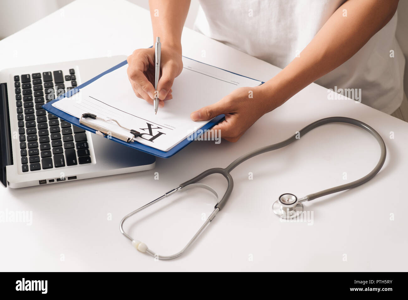 Close up on hands. Asian female doctor with laptop and writing ...