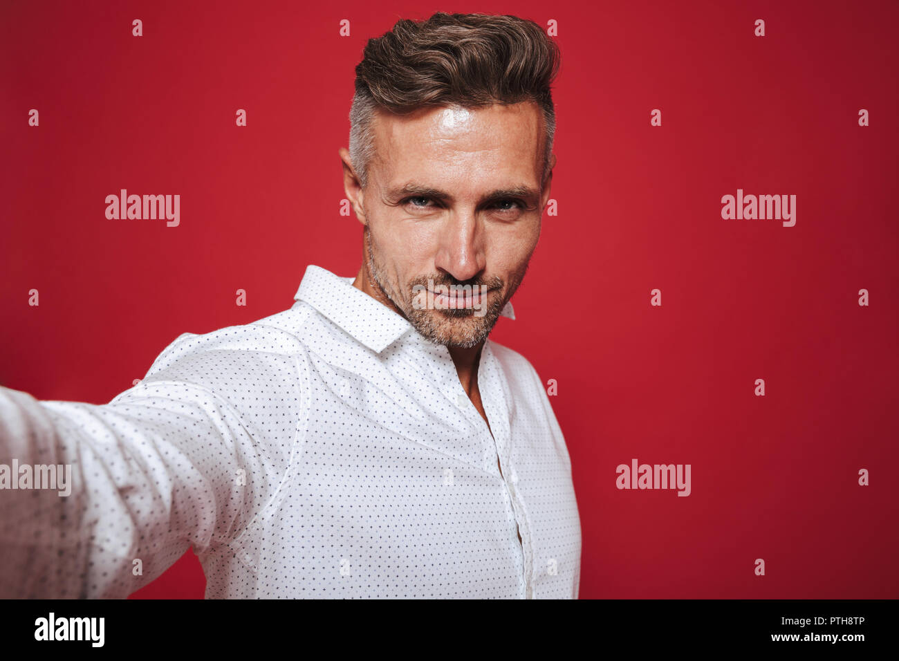 Handsome bearded man 30s in white shirt smiling and taking selfie photo ...