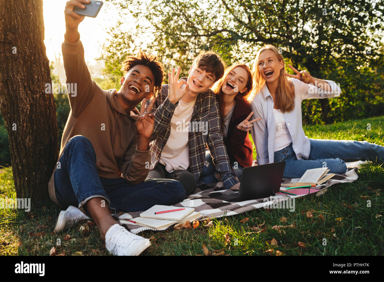 Group of cheerful multhiethnic students doing homework together at the ...