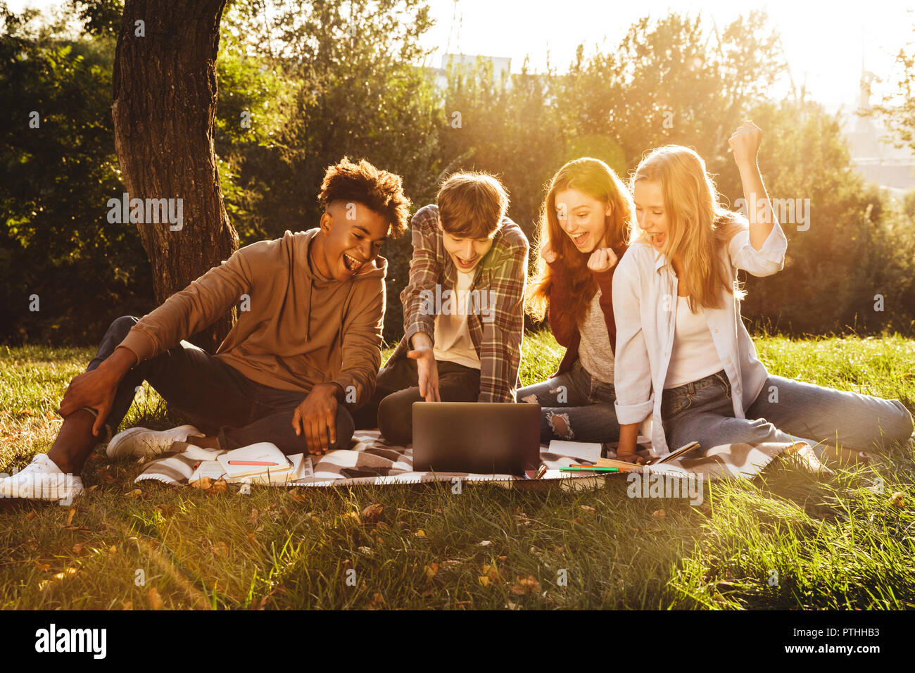 Group of cheerful multhiethnic students doing homework together at the ...