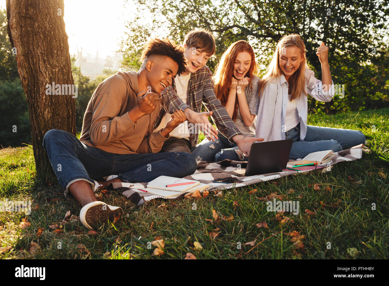Group of joyful multhiethnic students doing homework together at the ...