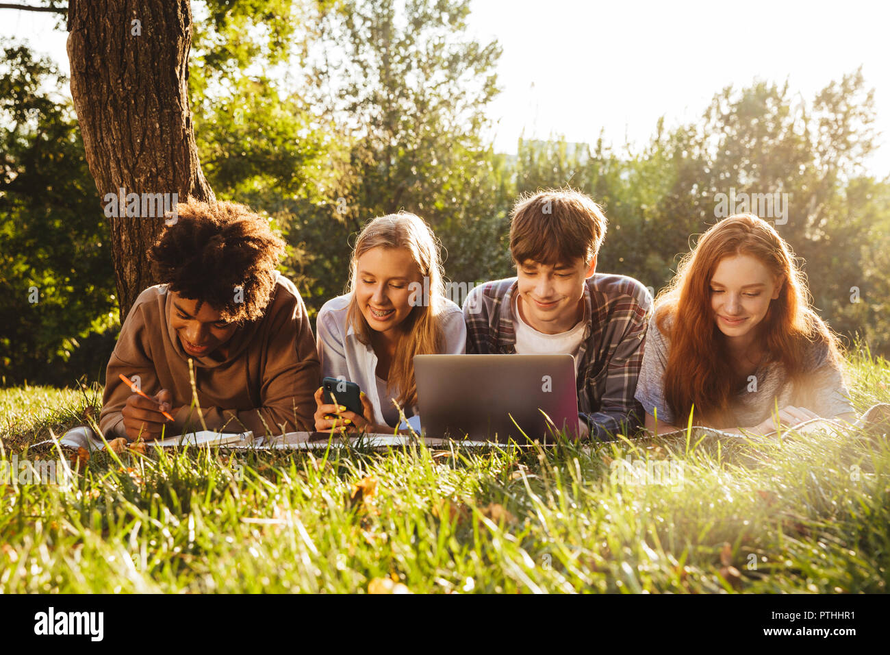 Group of happy multhiethnic students doing homework together at the ...