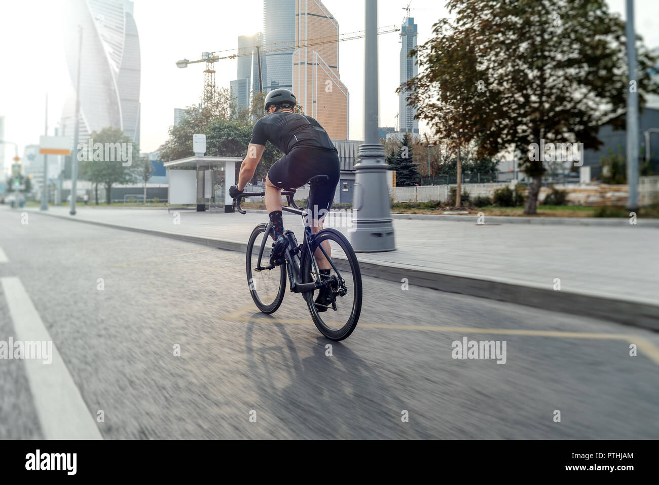 Athletic sportsman riding professional bike next to modern buildings on ...