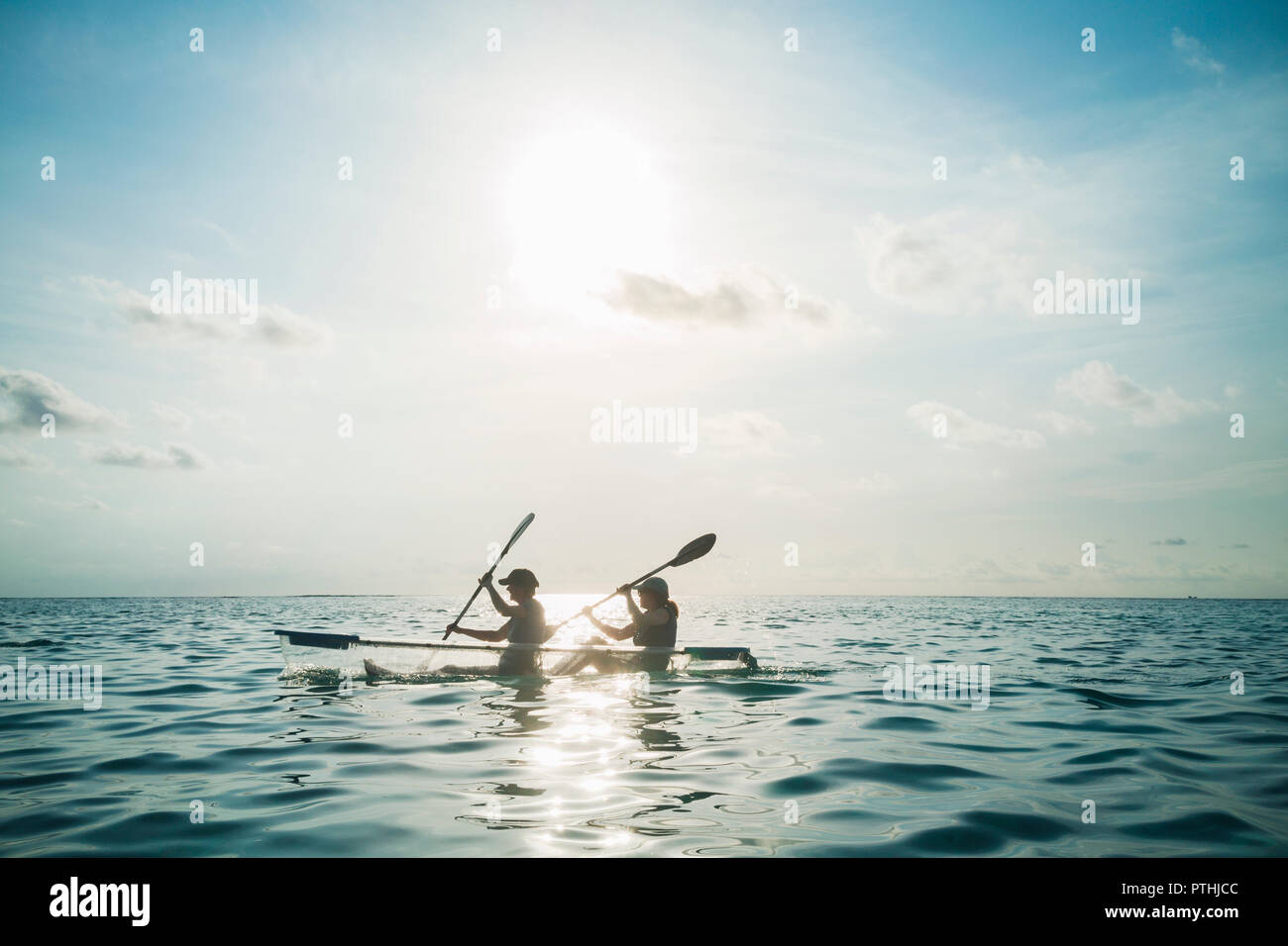 Women in clear bottom canoe on sunny, idyllic ocean, Maldives, Indian ...