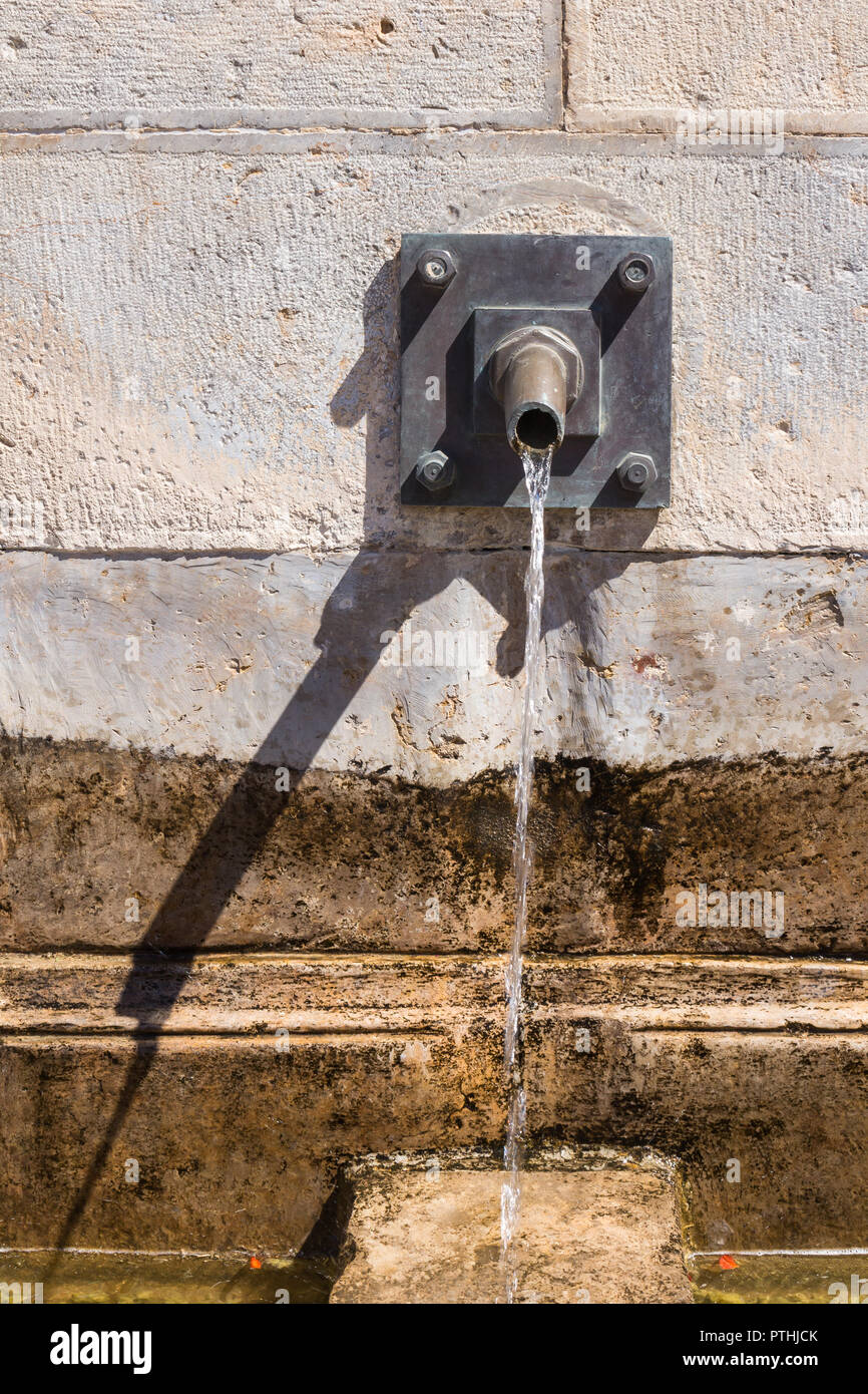 Wall made of stones with a water-tap and running water. Refreshment for ...