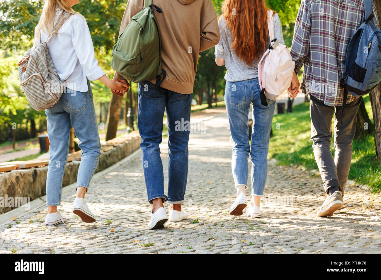Back view cropped image group of students with backpacks walking at the ...