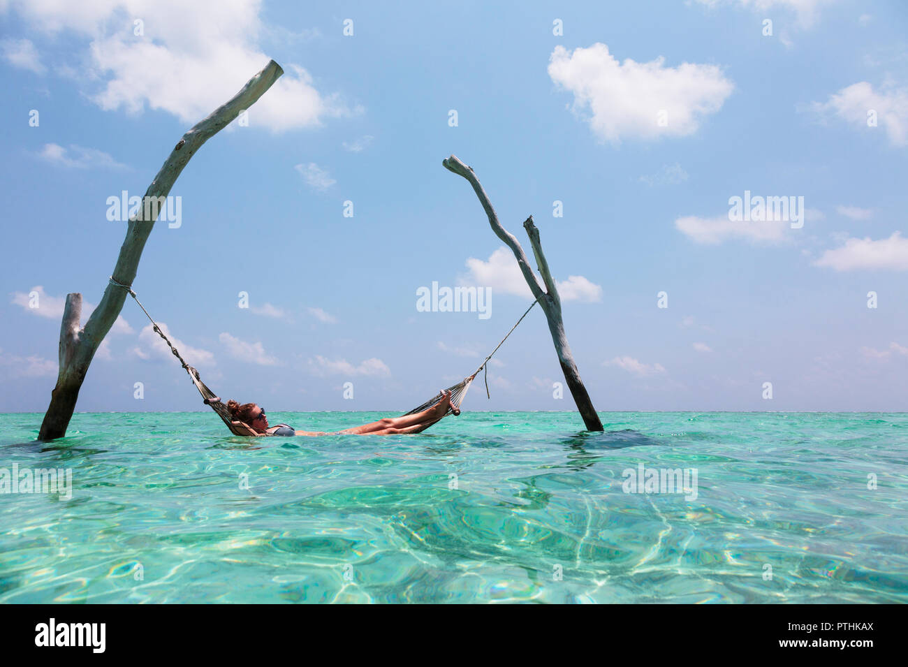 Woman laying in hammock over tranquil ocean, Maldives, Indian Ocean ...
