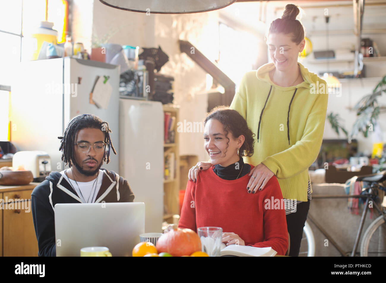 Young college student roommates studying at kitchen table in apartment ...