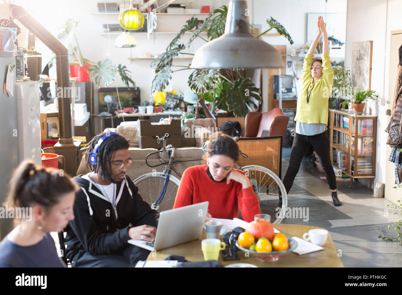 Young college student roommates studying and stretching in apartment ...