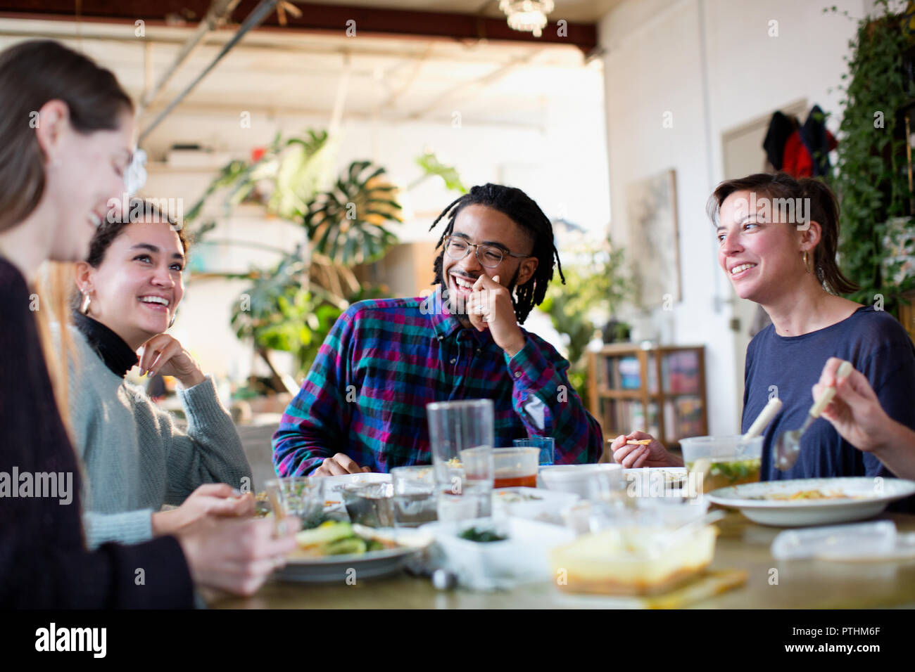 Young roommate friends enjoying takeout food at kitchen table in ...